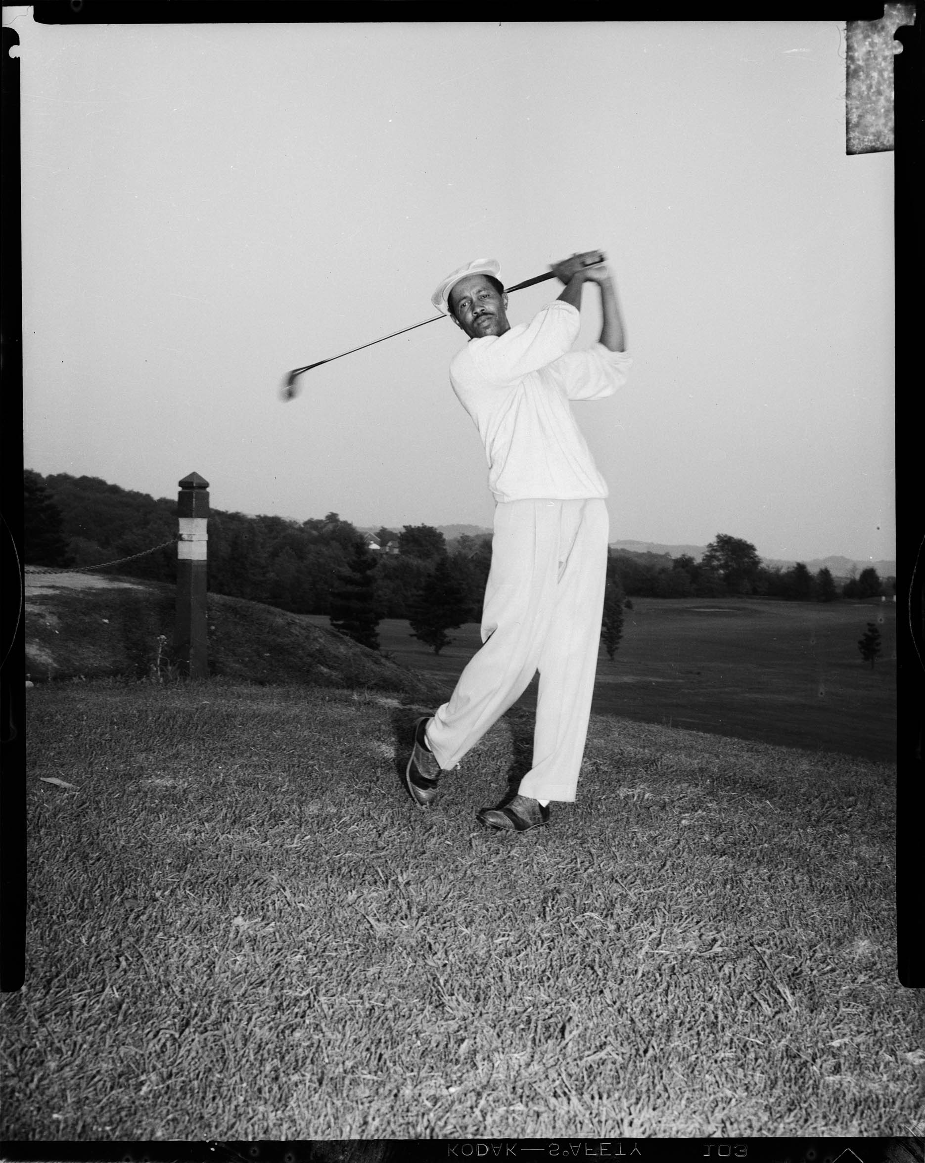 Portrait of golfer Ted Rhodes, swinging golf club on South Park golf ...